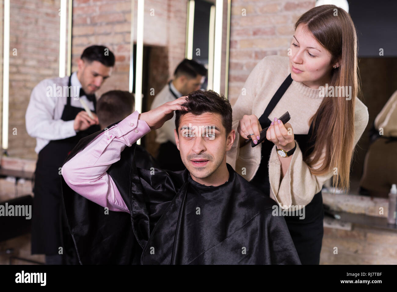 Man unpleasantly surprised by haircut from young woman hairdresser ...