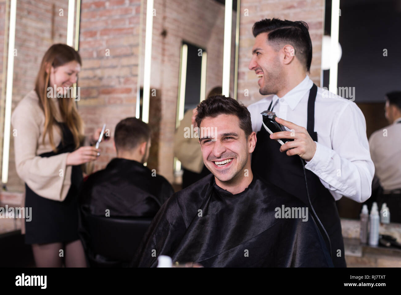 Professional hairdresser man doing styling of handsome guy with ...