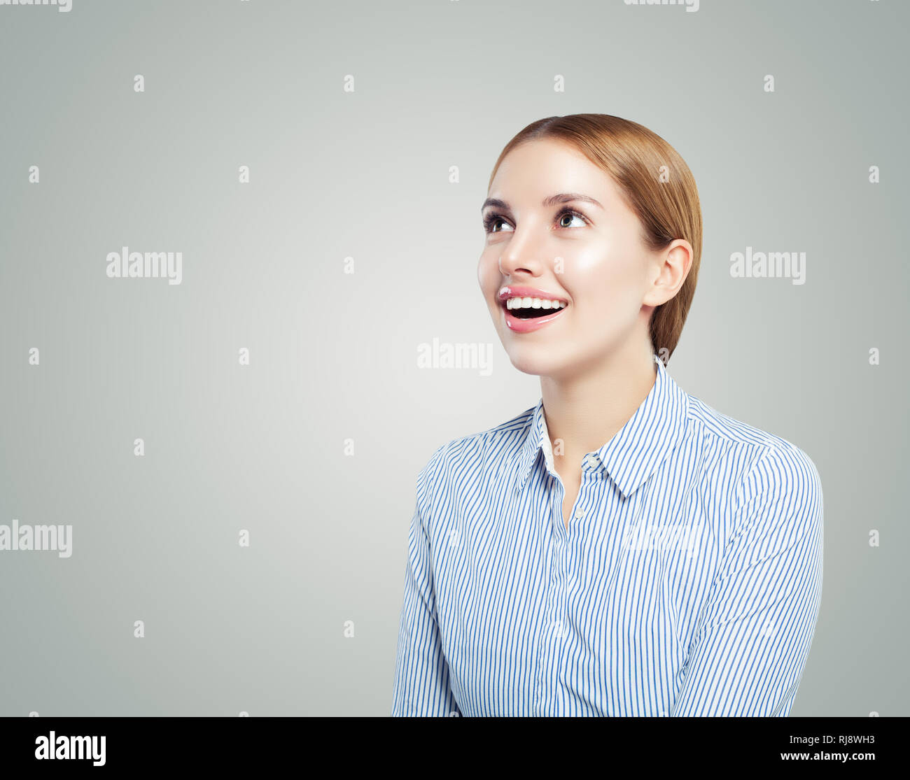 Surprised woman looking up on white background. Cheerful girl portrait ...