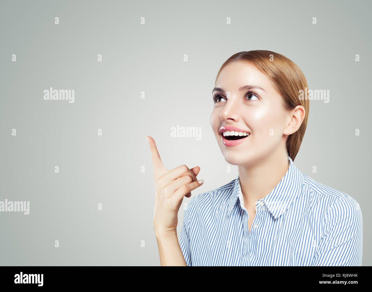 Happy surprised woman pointing up on white background Stock Photo - Alamy