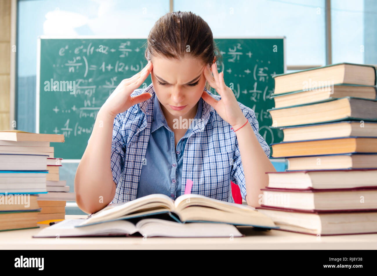 Female student with many books sitting in the classroom Stock Photo - Alamy