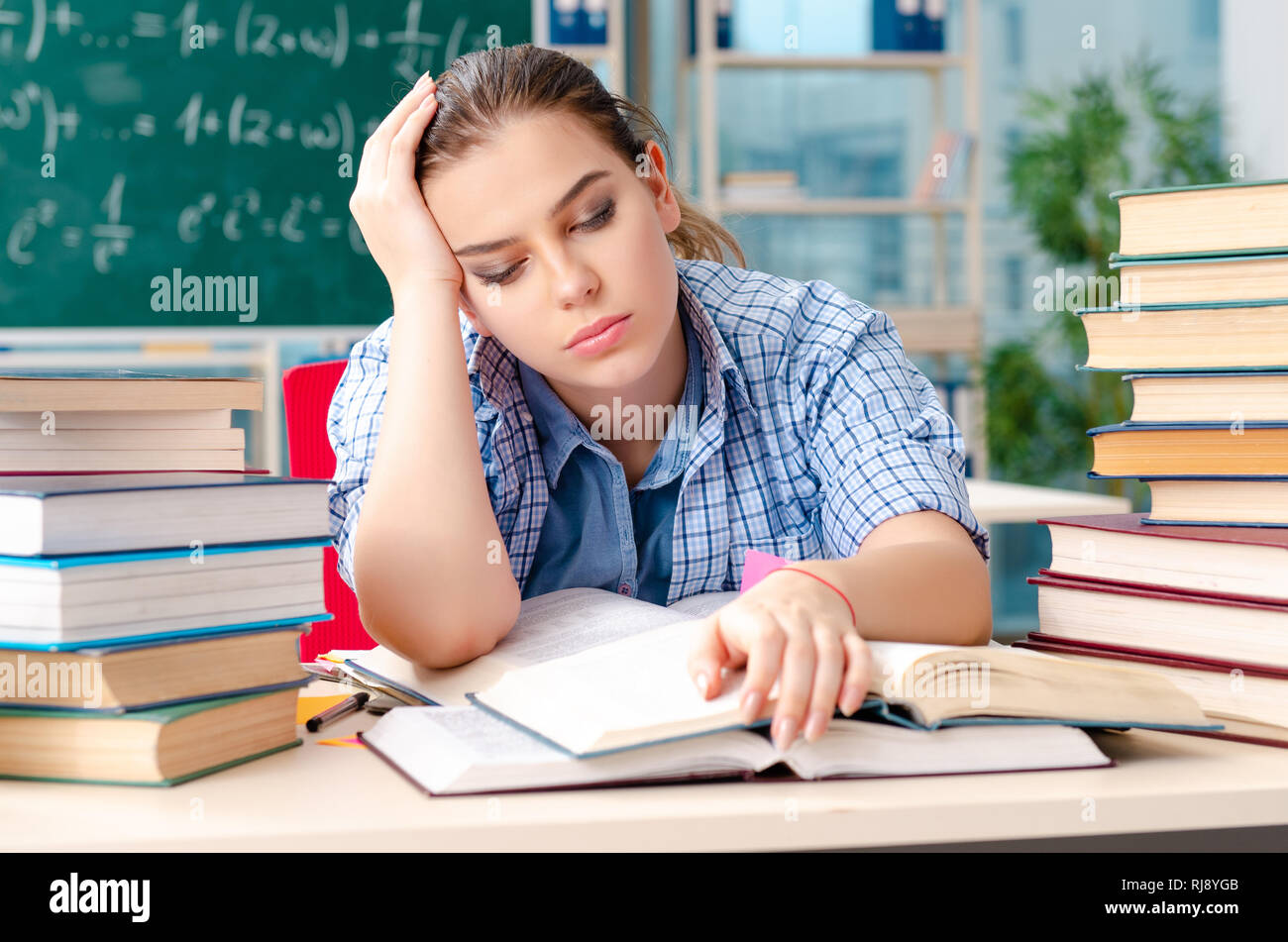 Female student with many books sitting in the classroom Stock Photo - Alamy