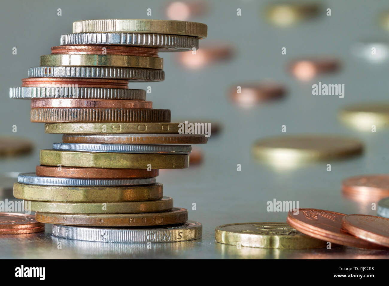 Pile of shiny coins different sizes and colors stacked unevenly on each ...