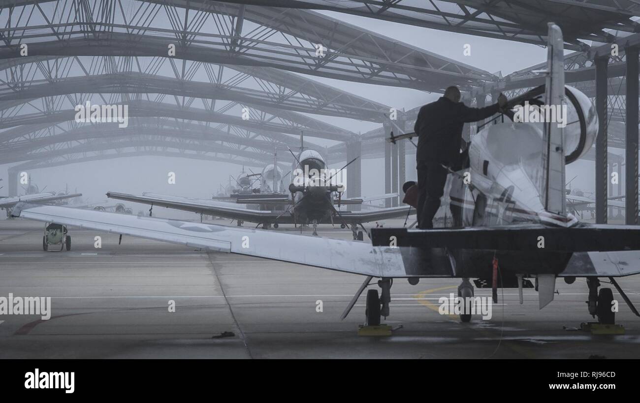 An L3 Communications maintainer preps a T-6 as fog covers the ...