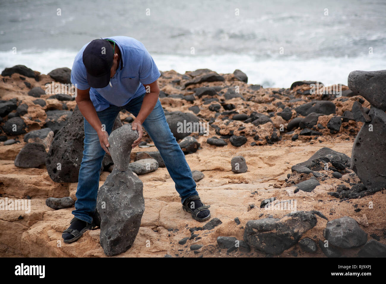 Man balancing rocks on beach Stock Photo - Alamy