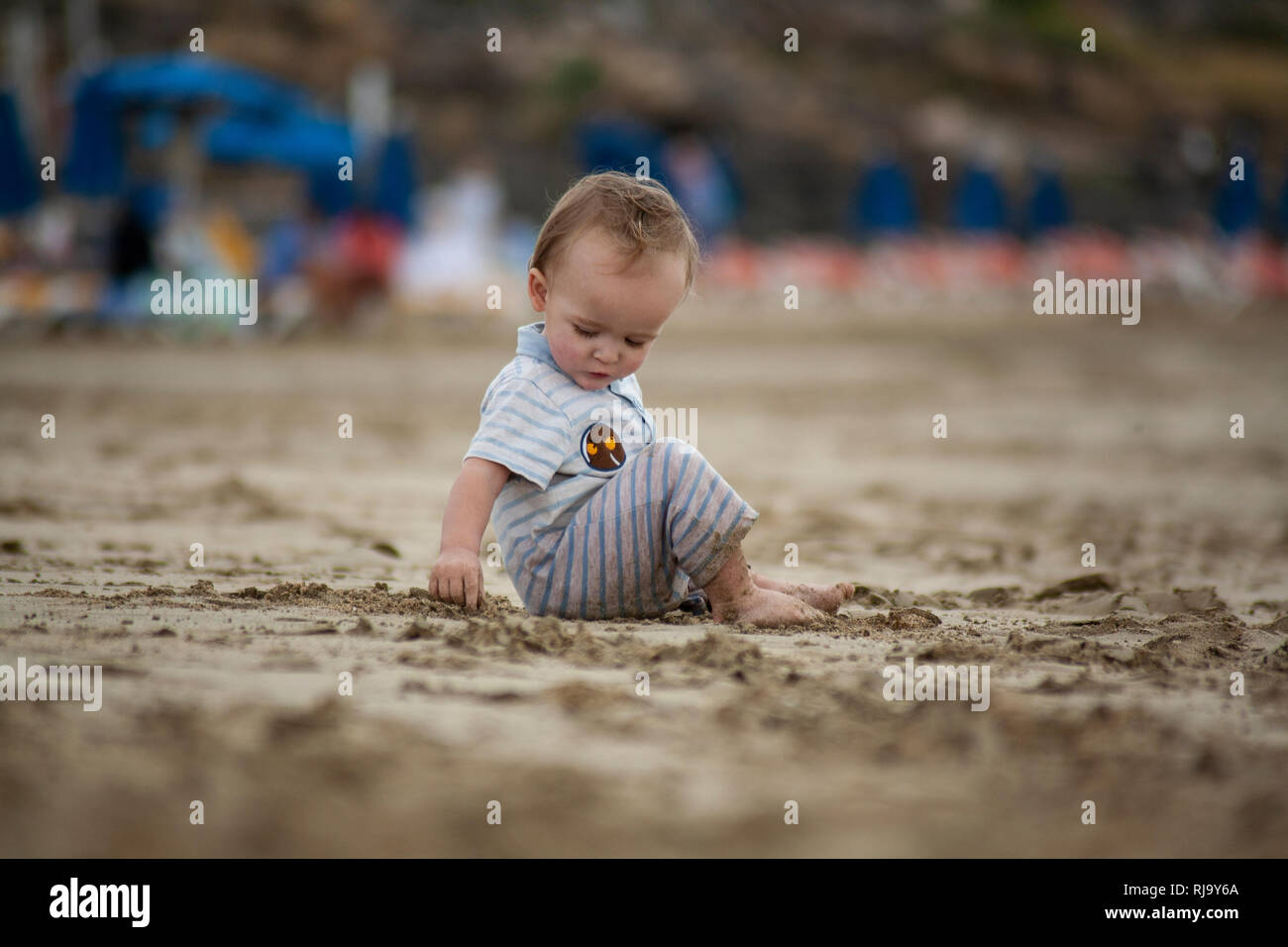 Baby Playing on beach with sand Stock Photo - Alamy