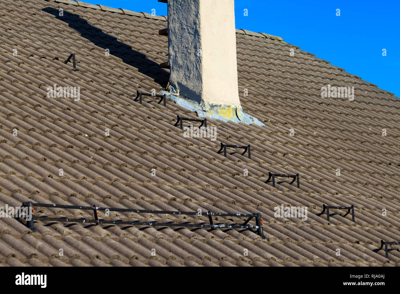 The roofing tiles house roof with chimney and safety metal ladder to ...