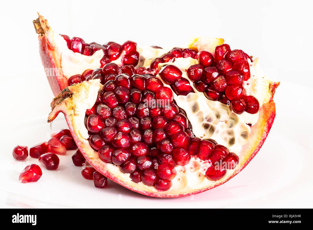 splitted pomegranate fruit on plate on white background Stock Photo - Alamy
