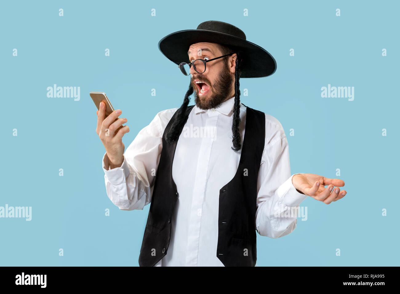 Portrait of a young orthodox Hasdim Jewish man with mobile phone at ...