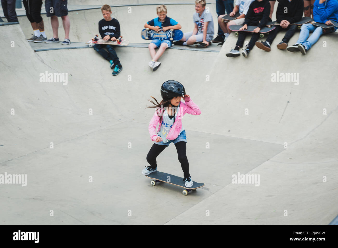 A young girl being watched by boys as she skates at The Level Skatepark ...