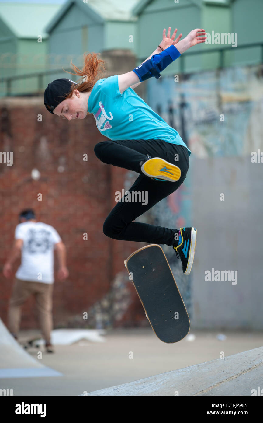 A teenage girl jumps in the air while performing a trick while skating ...