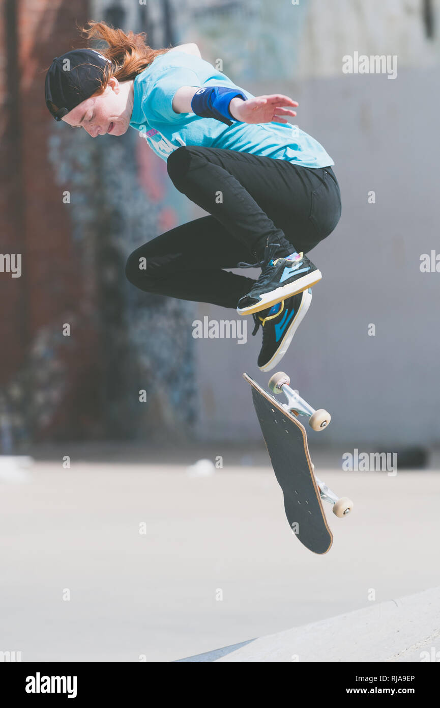 A teenage girl jumps in the air while performing a trick while skating ...