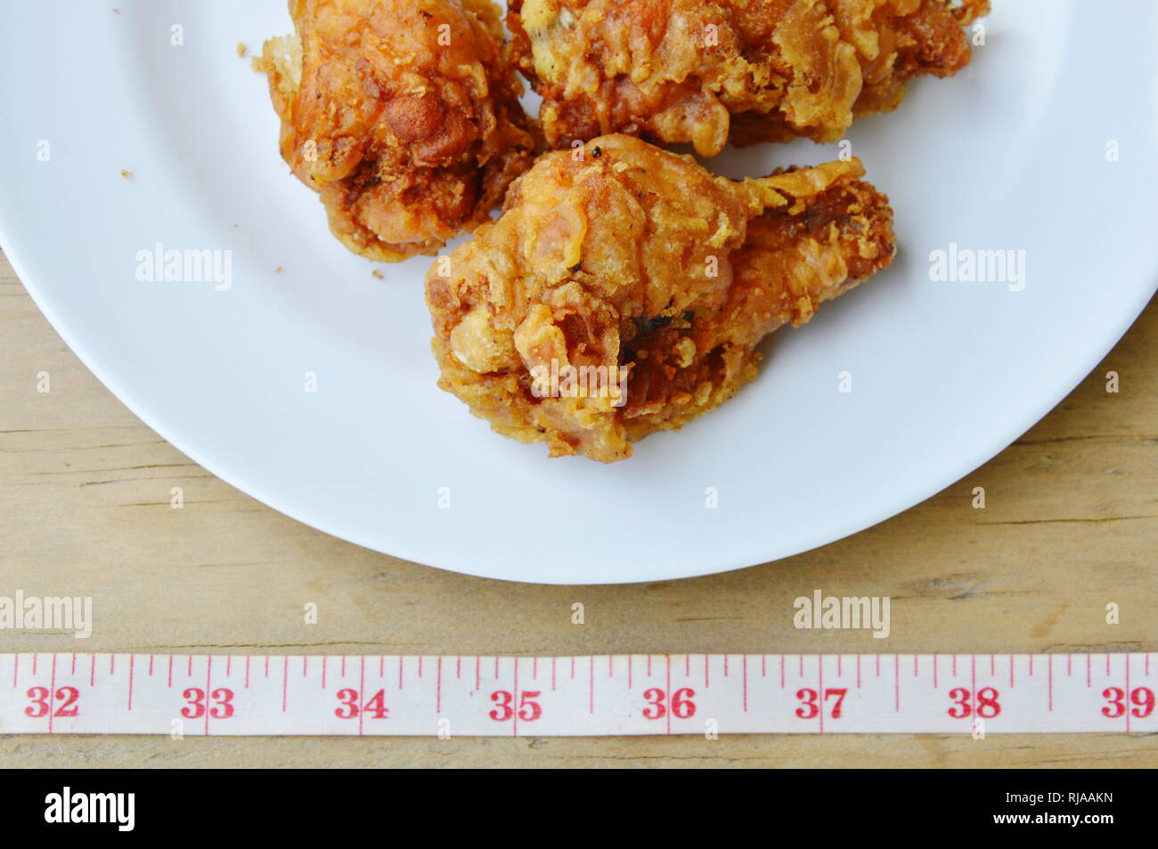fried chicken leg and measuring tape for check waistline after eat ...