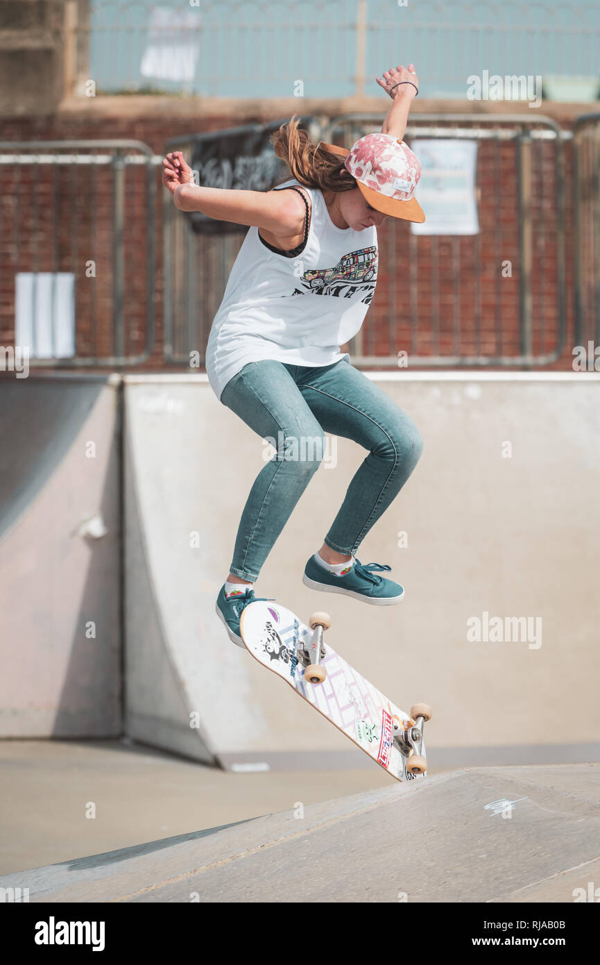 A teenage girl jumps in the air while performing a trick while skating ...