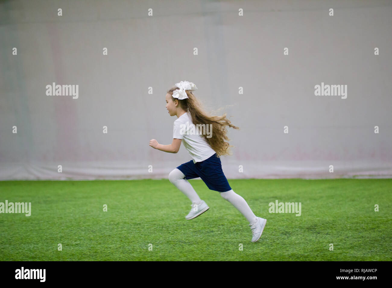 Playing football indoors. A little girl running on a football field ...