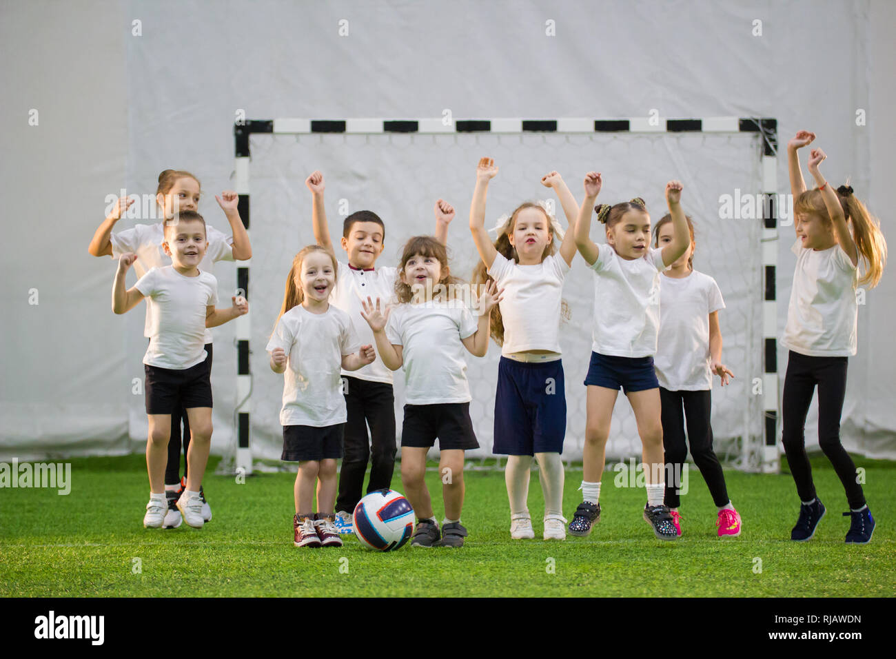 Little kids playing football indoors. Children football team. Hands up ...