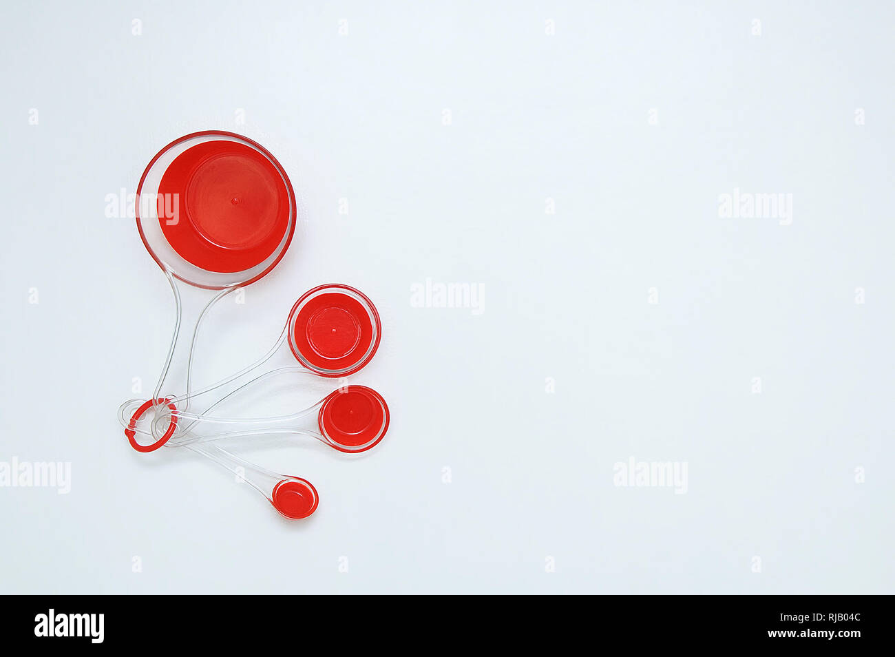 Red plastic measuring spoons for cooking. White background. View from ...