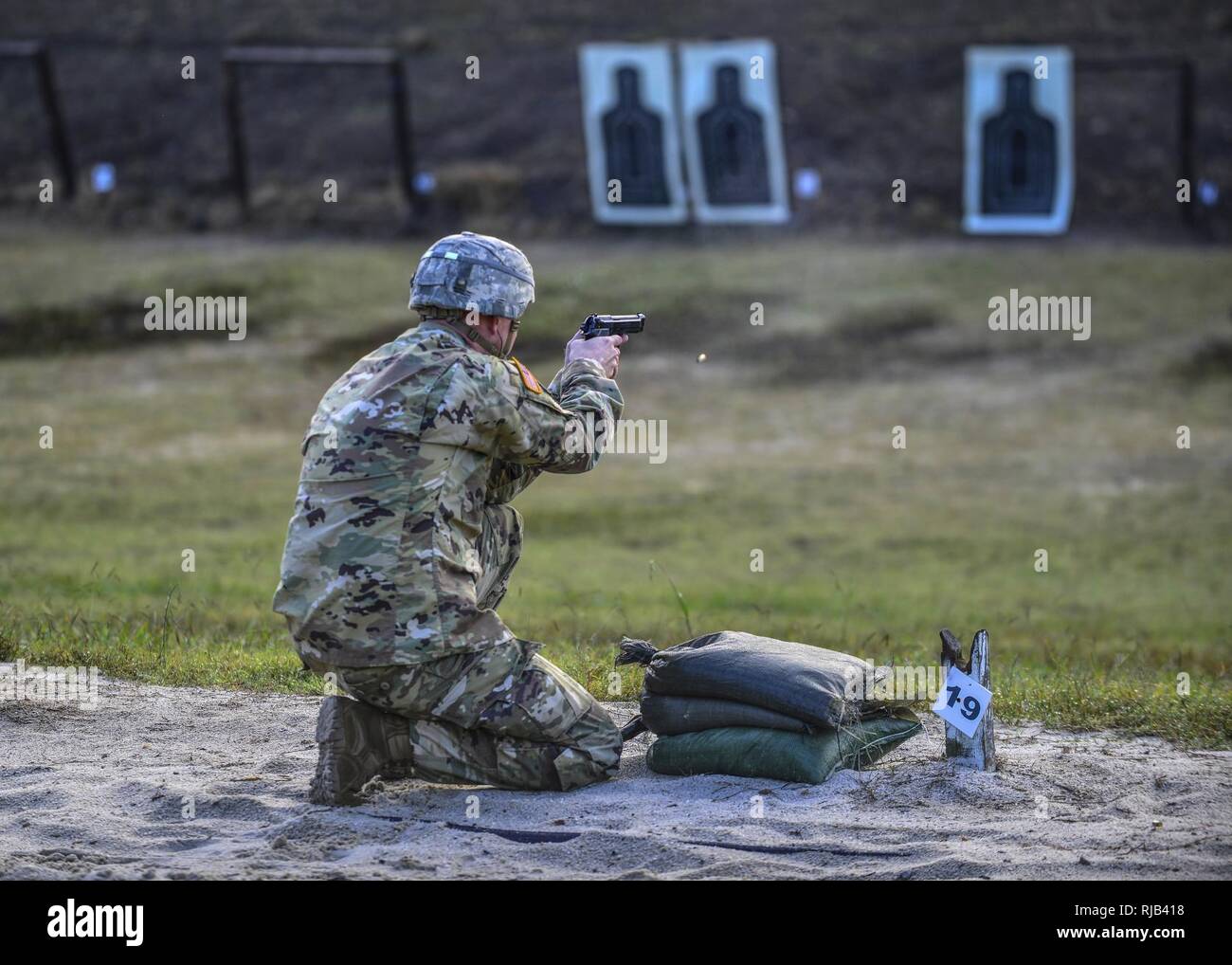 An U.S. Army Soldier fires a 9 mm pistol in the kneeling unsupported ...