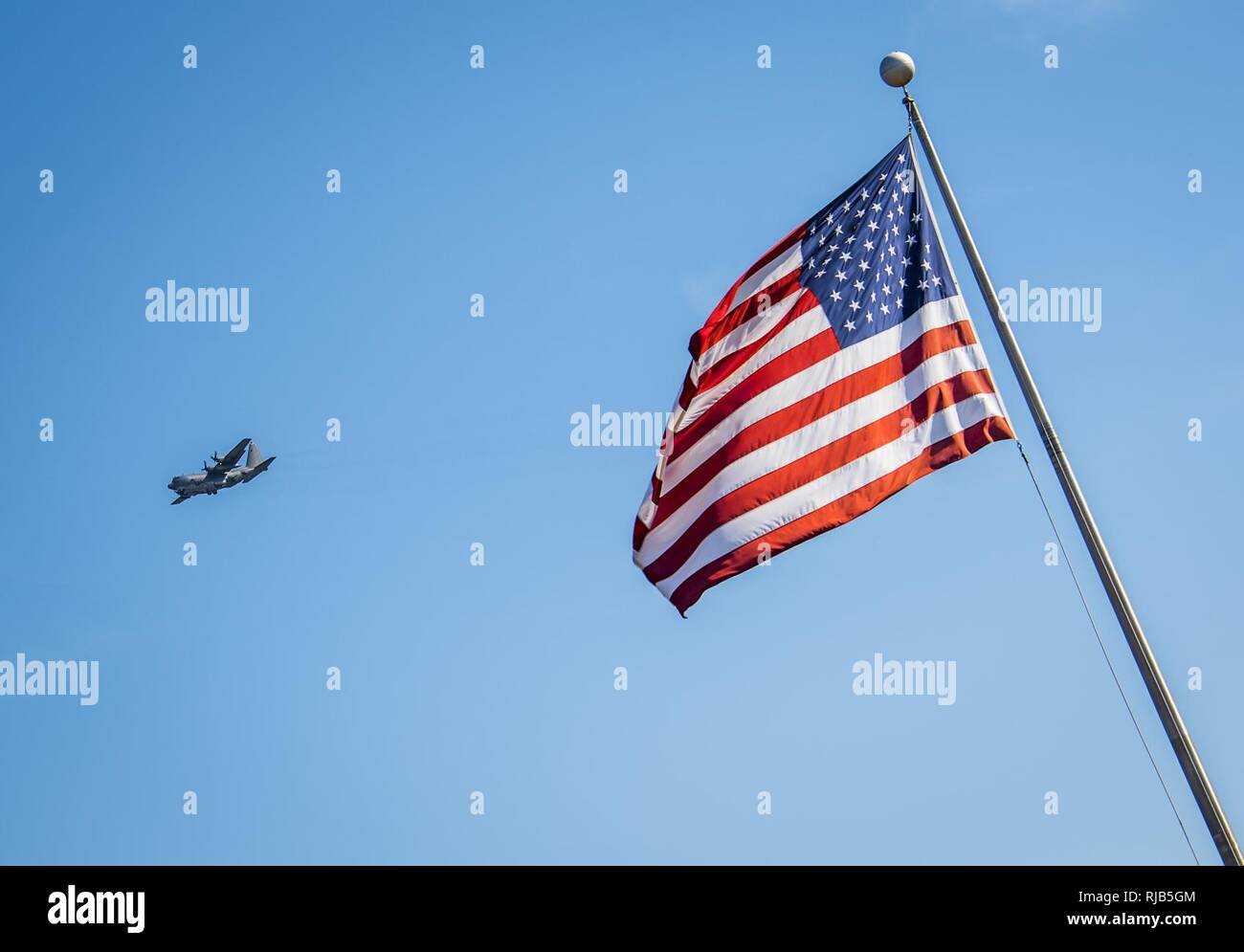 A C-130 flies by the American flag in front of the 96th Test Wing ...