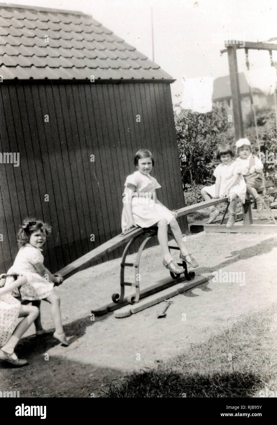 Four young children playing on a see-saw Stock Photo - Alamy