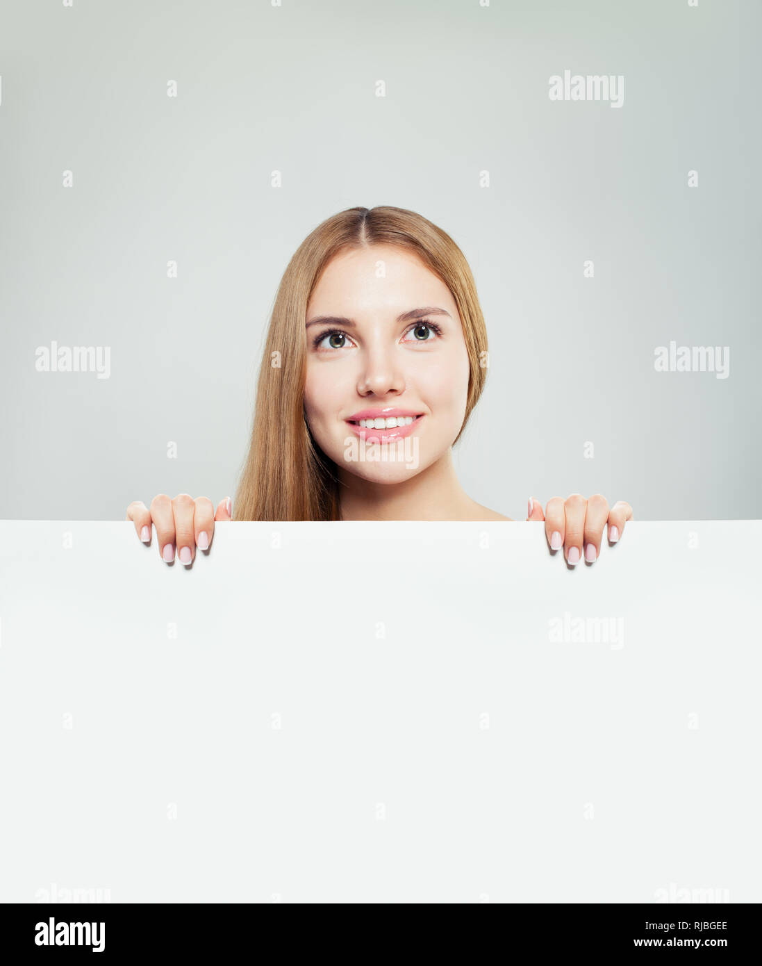 Happy woman looking up and holding white empty paper board background ...