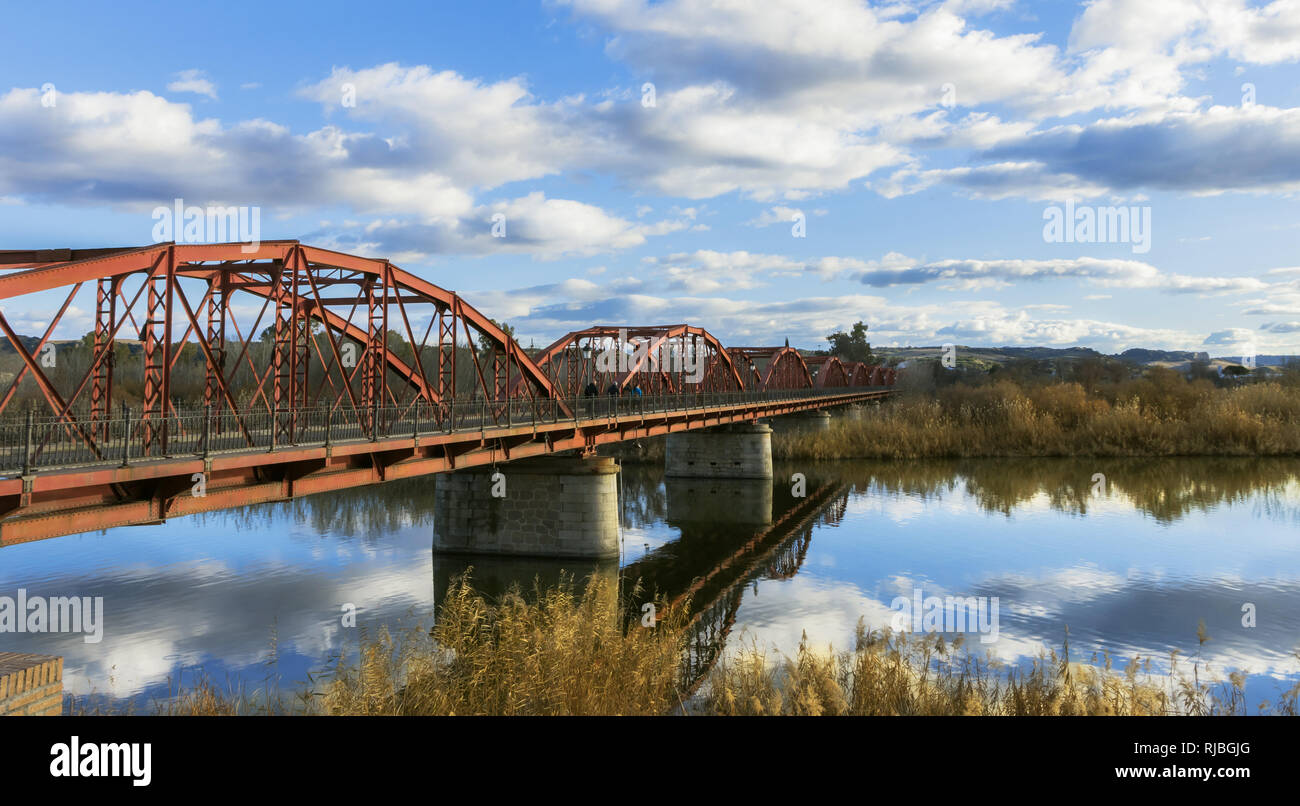 Red iron bridge over the Tagus River with blue sky and white clouds ...