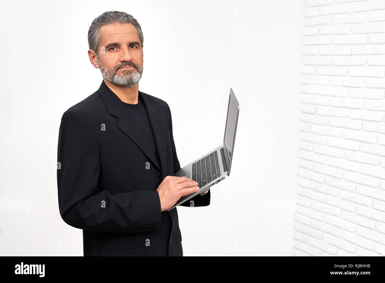 Bearded man holding modern notebook in hands, looking at camera. Mature ...