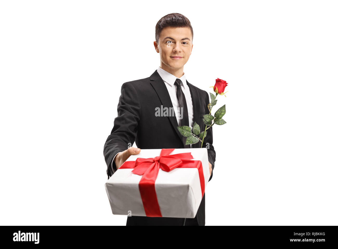 Handsome young man in a suit giving a present and a red rose isolated ...