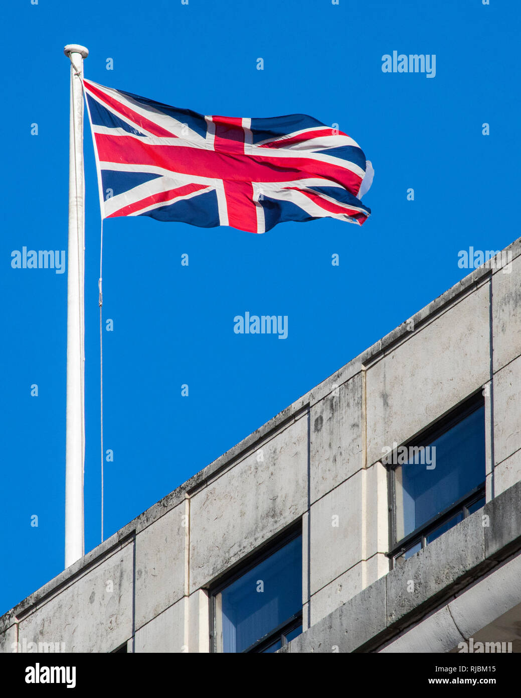 A view of a Union flag flying over a clear blue sky Stock Photo - Alamy