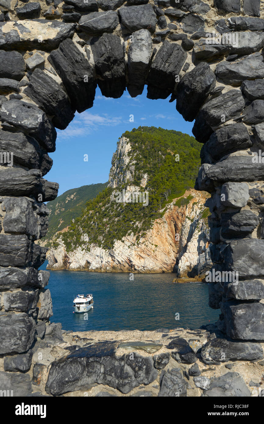 View through stone arch of boat, sea and cliffs from Portovenere Church ...
