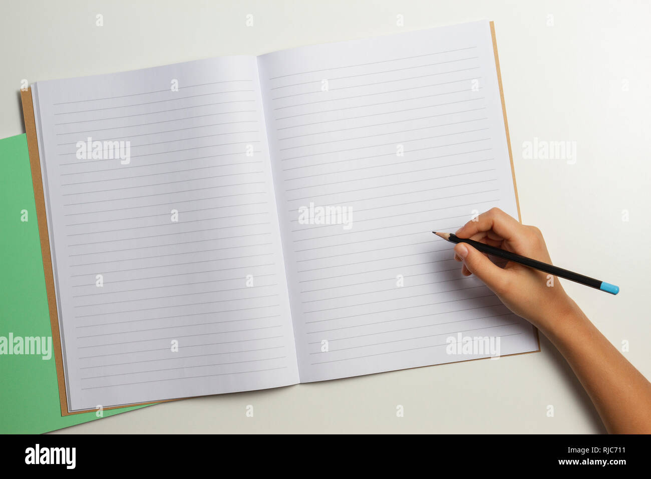 Kid hand with pencil and open notebook on white background. Top view ...