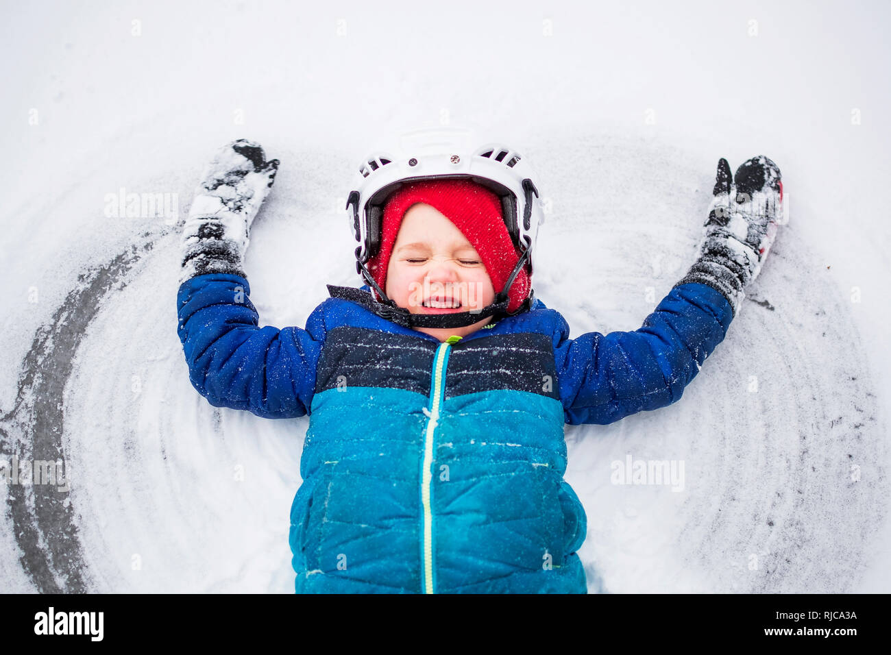 Boy lying on frozen lake making a snow angel, Wisconsin, United States ...