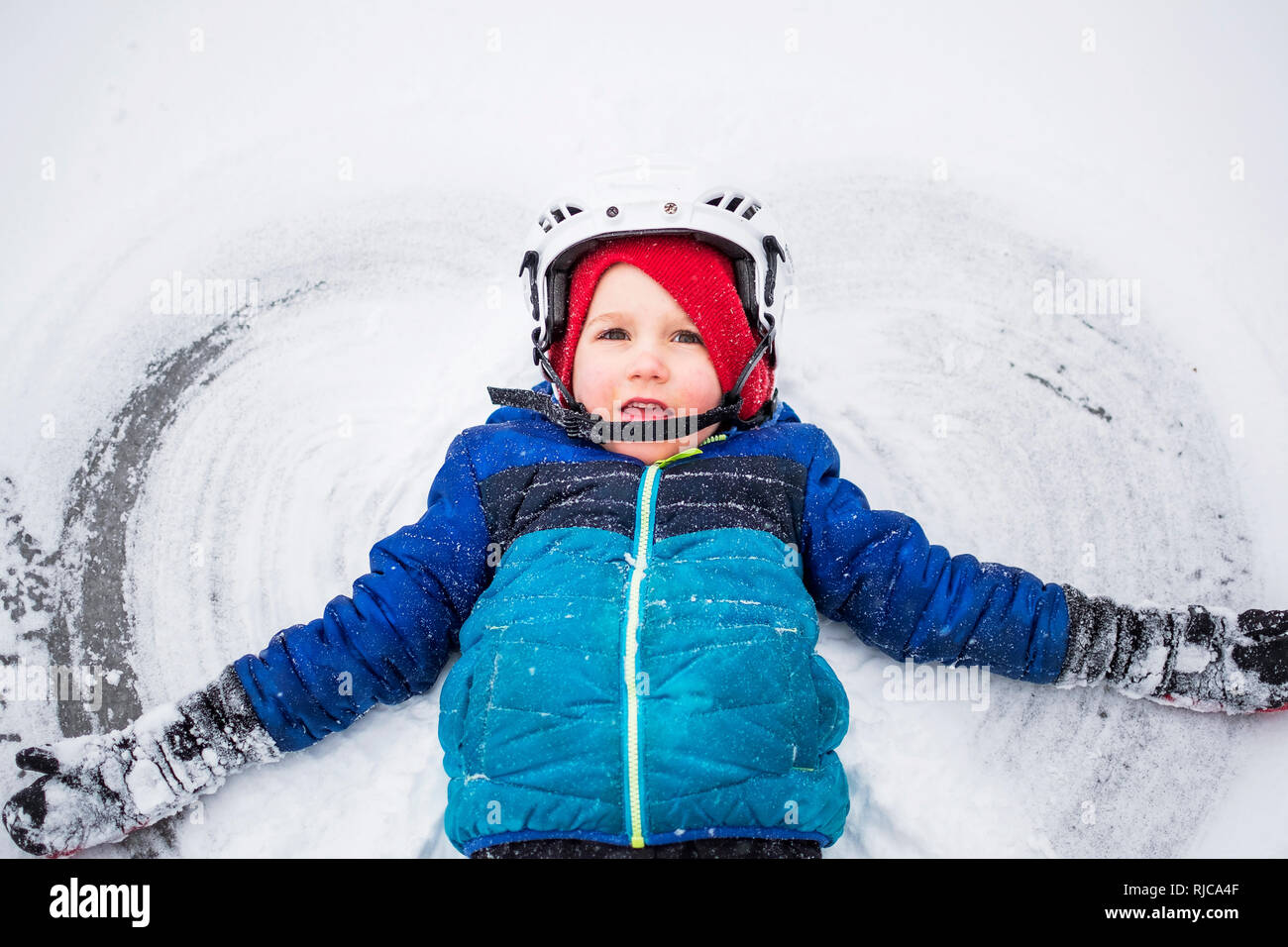 Boy lying on frozen lake making a snow angel, Wisconsin, United States ...