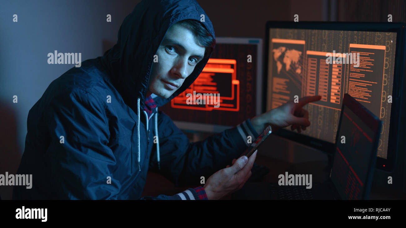 The male hacker in the hood is pointing his finger at the display ...