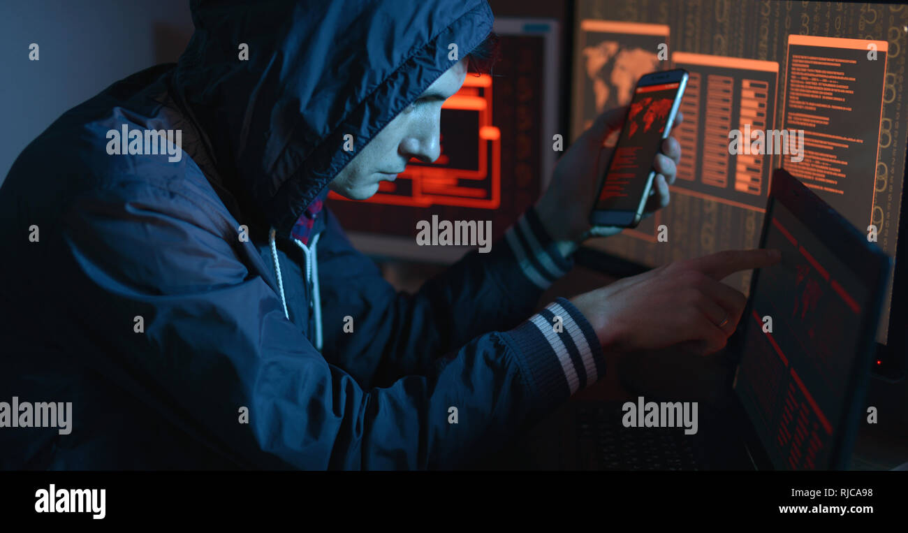 The male hacker in the hood is pointing his finger at the display ...