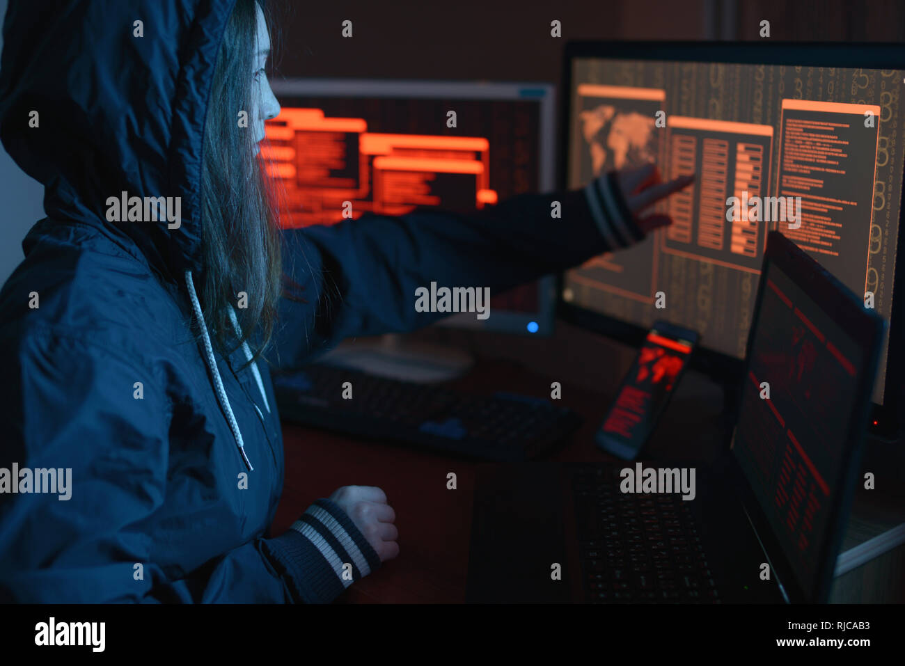 Girl hacker is pointing her finger at the display indicating the ...
