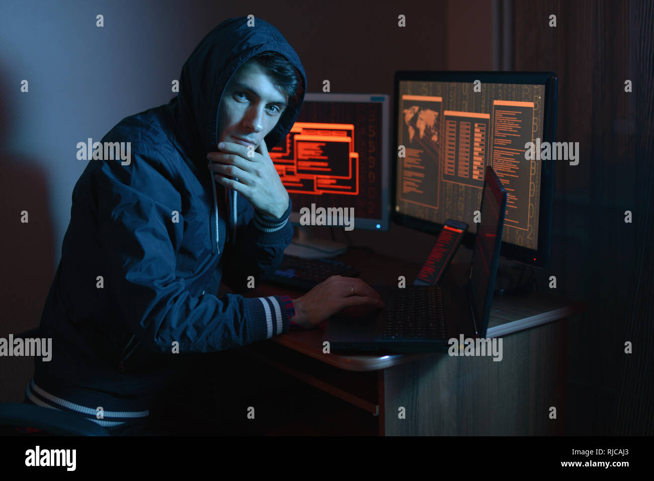 Male in the hood looking in the camera. Hacker attacks and online fraud ...