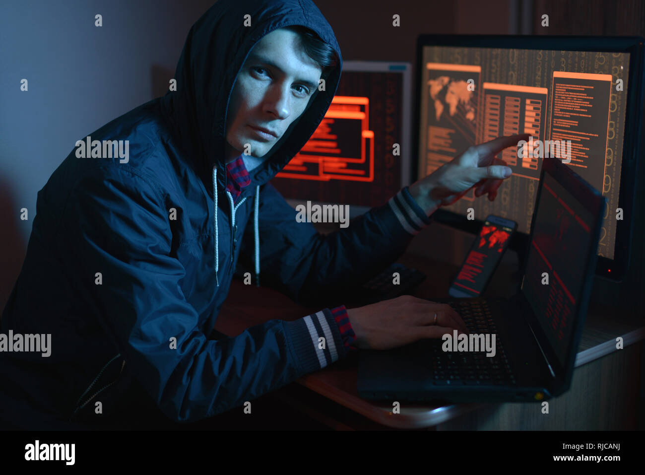 Male in the hood looking in the camera. Hacker attacks and online fraud ...