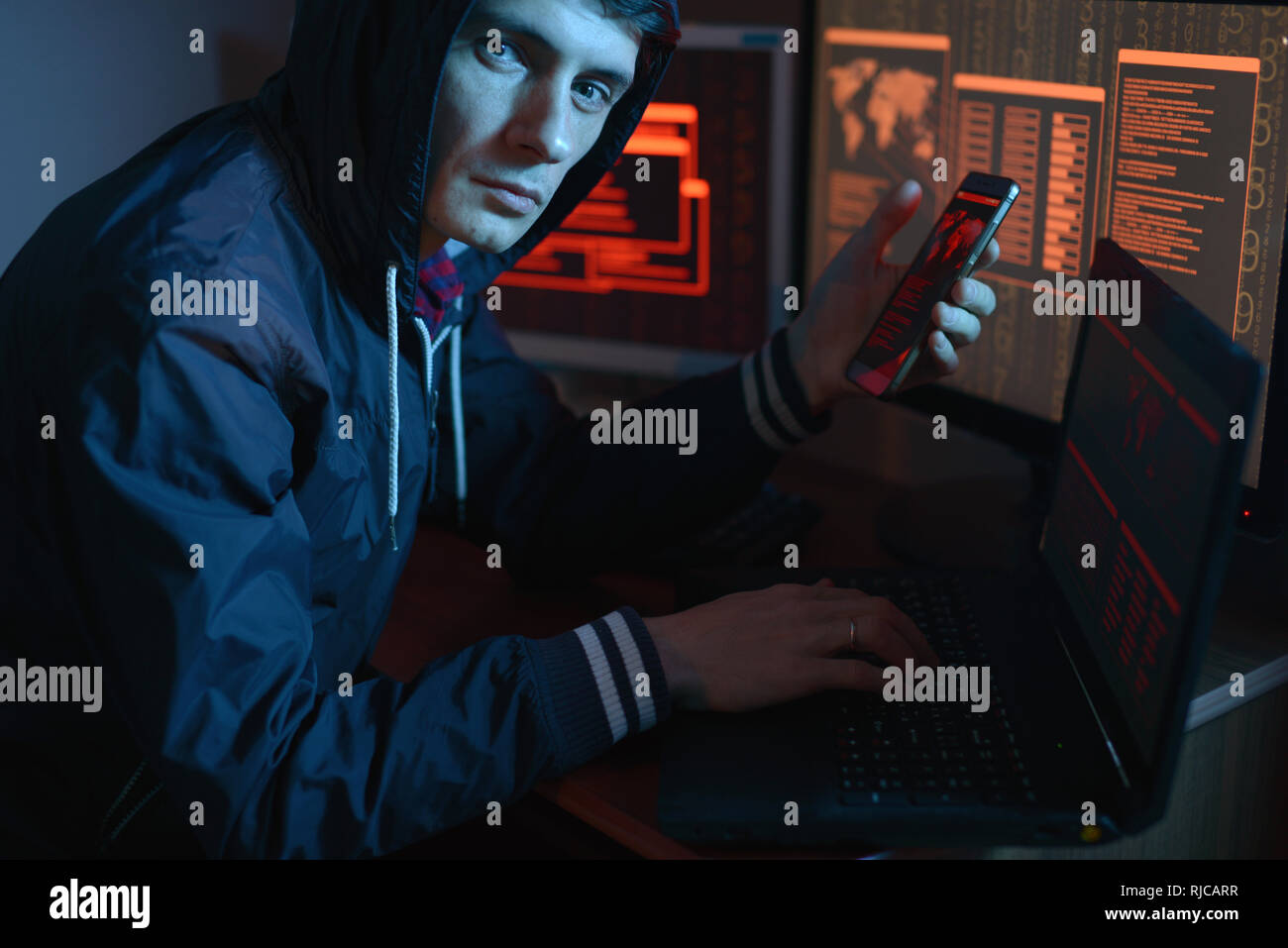 Male in the hood looking in the camera. Hacker attacks and online fraud ...