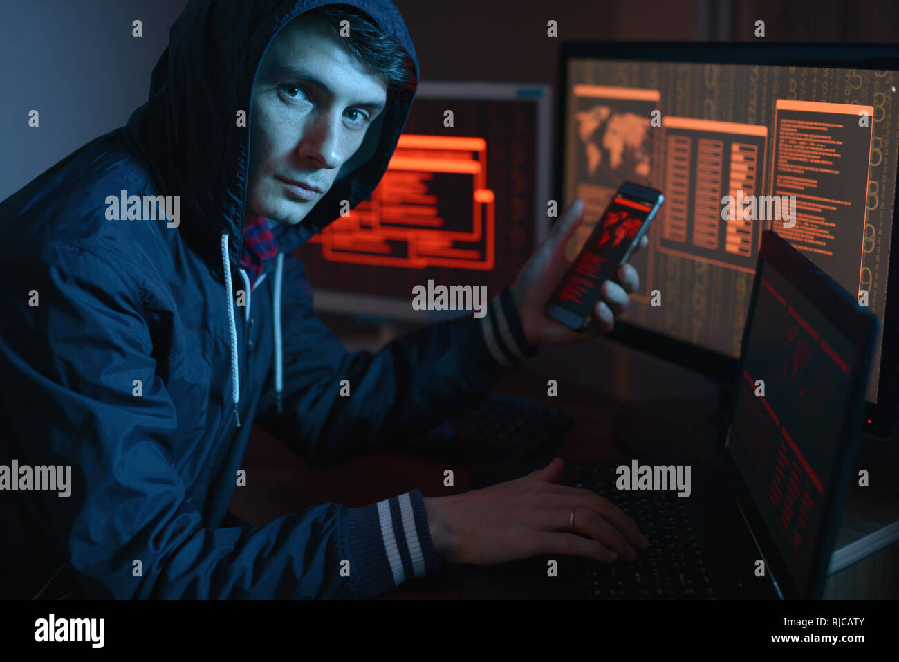 Male in the hood looking in the camera. Hacker attacks and online fraud ...