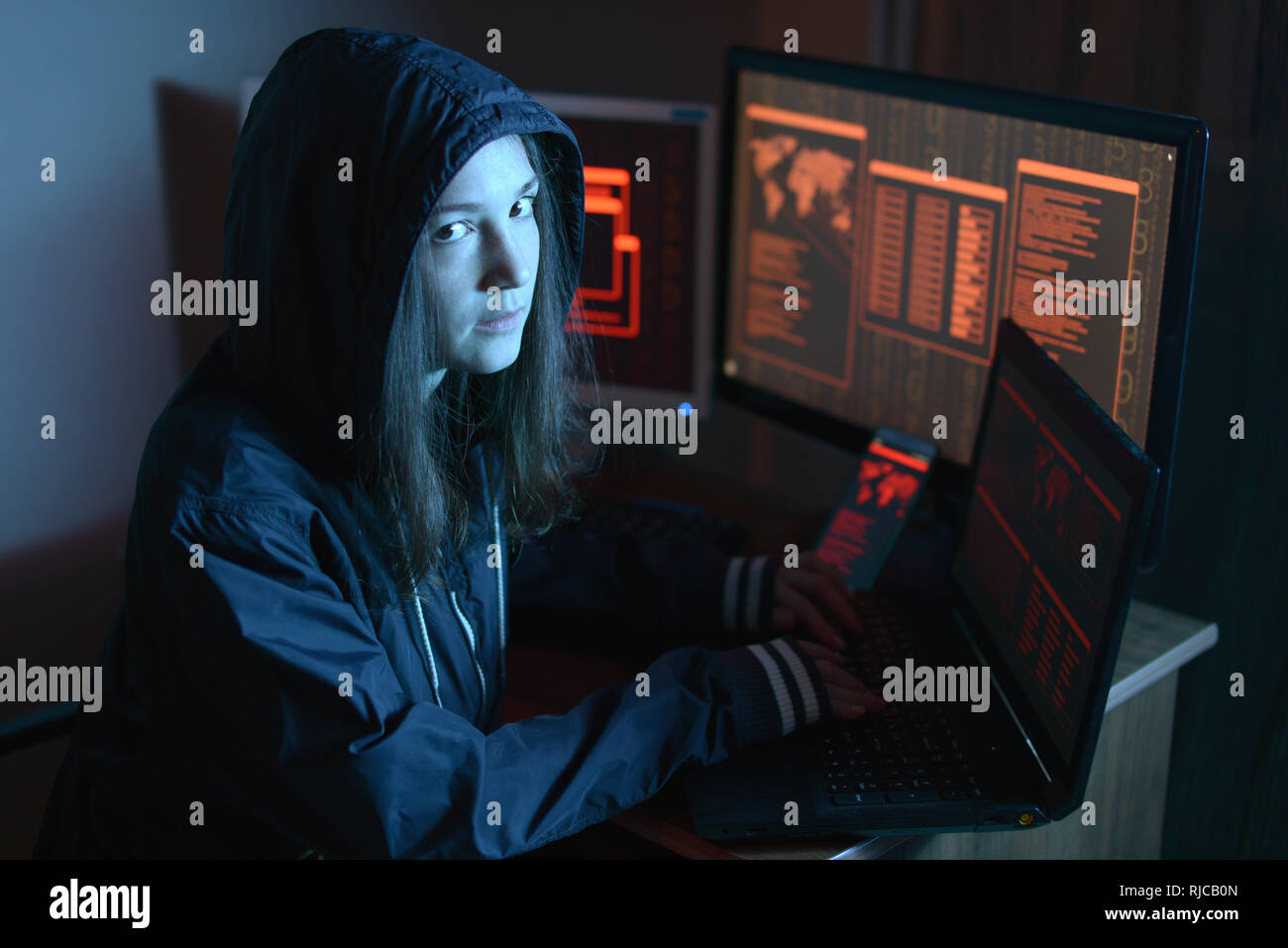 Girl in the hood looking in the camera. Hacker attacks and online fraud ...