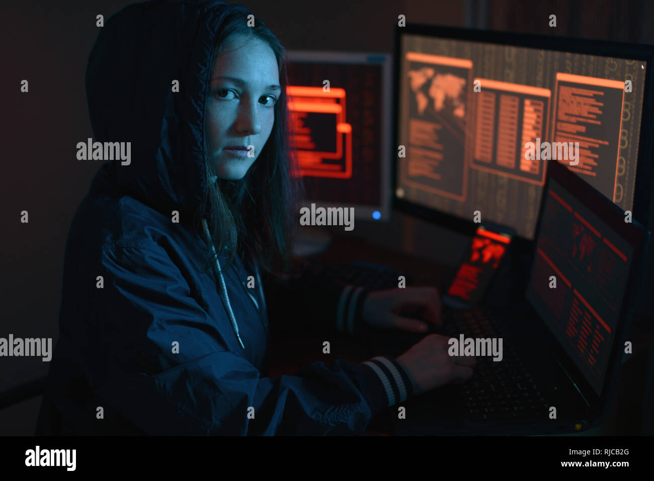 Girl in the hood looking in the camera. Hacker attacks and online fraud ...