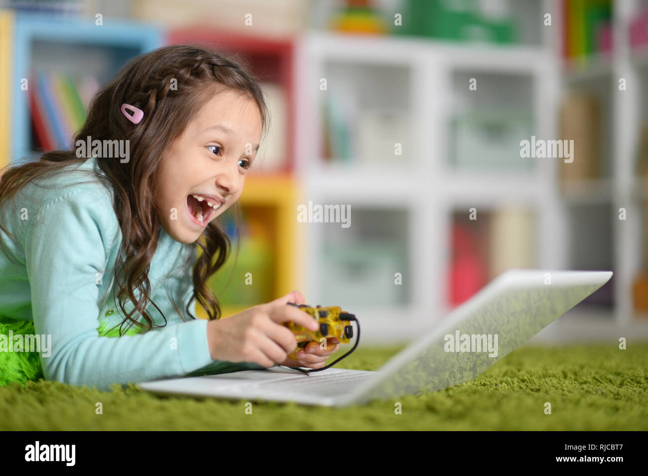 Cute girl playing computer game with laptop Stock Photo - Alamy