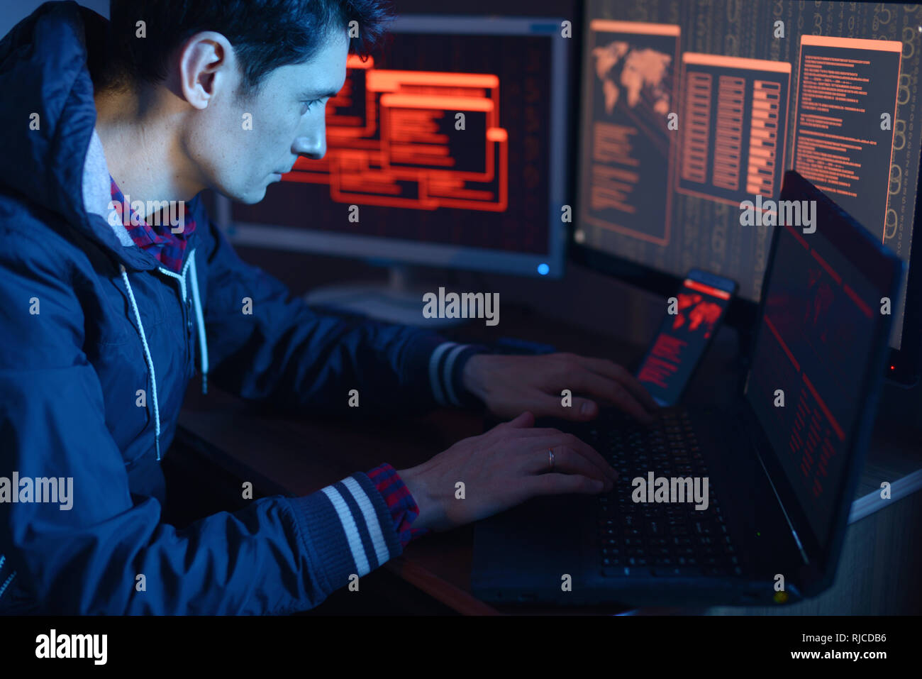 Hacker typing program code while committing a cybercrime hacking a system firewall on the ...