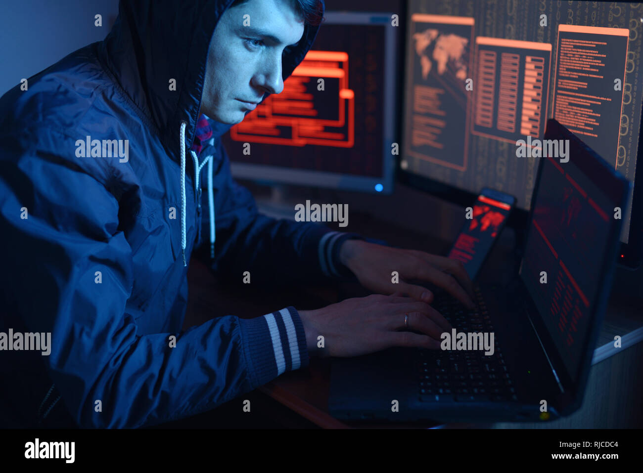 Hacker typing program code while committing a cybercrime hacking a system firewall on the ...