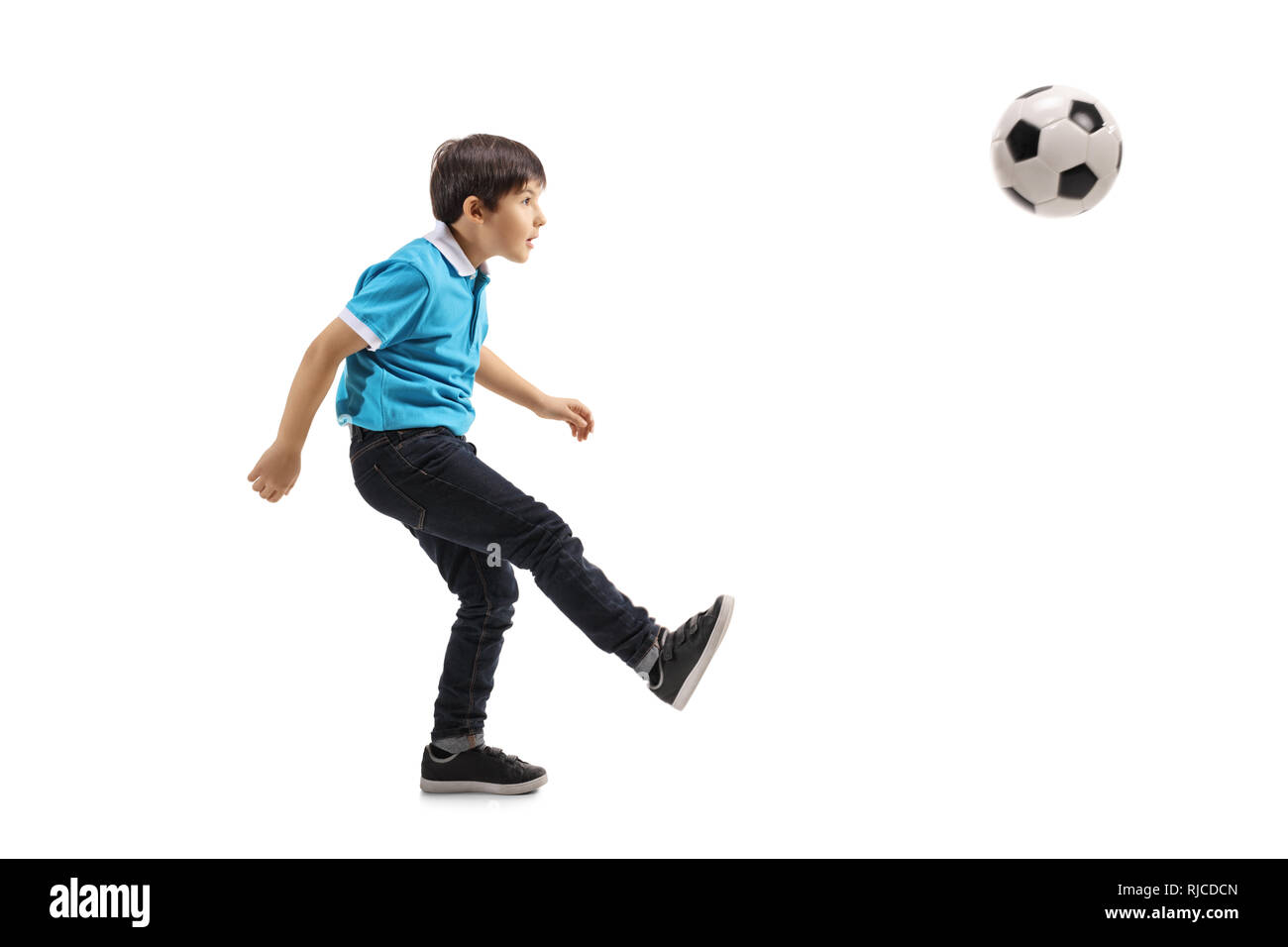 Full length shot of a little boy kicking a soccer ball isolated on ...