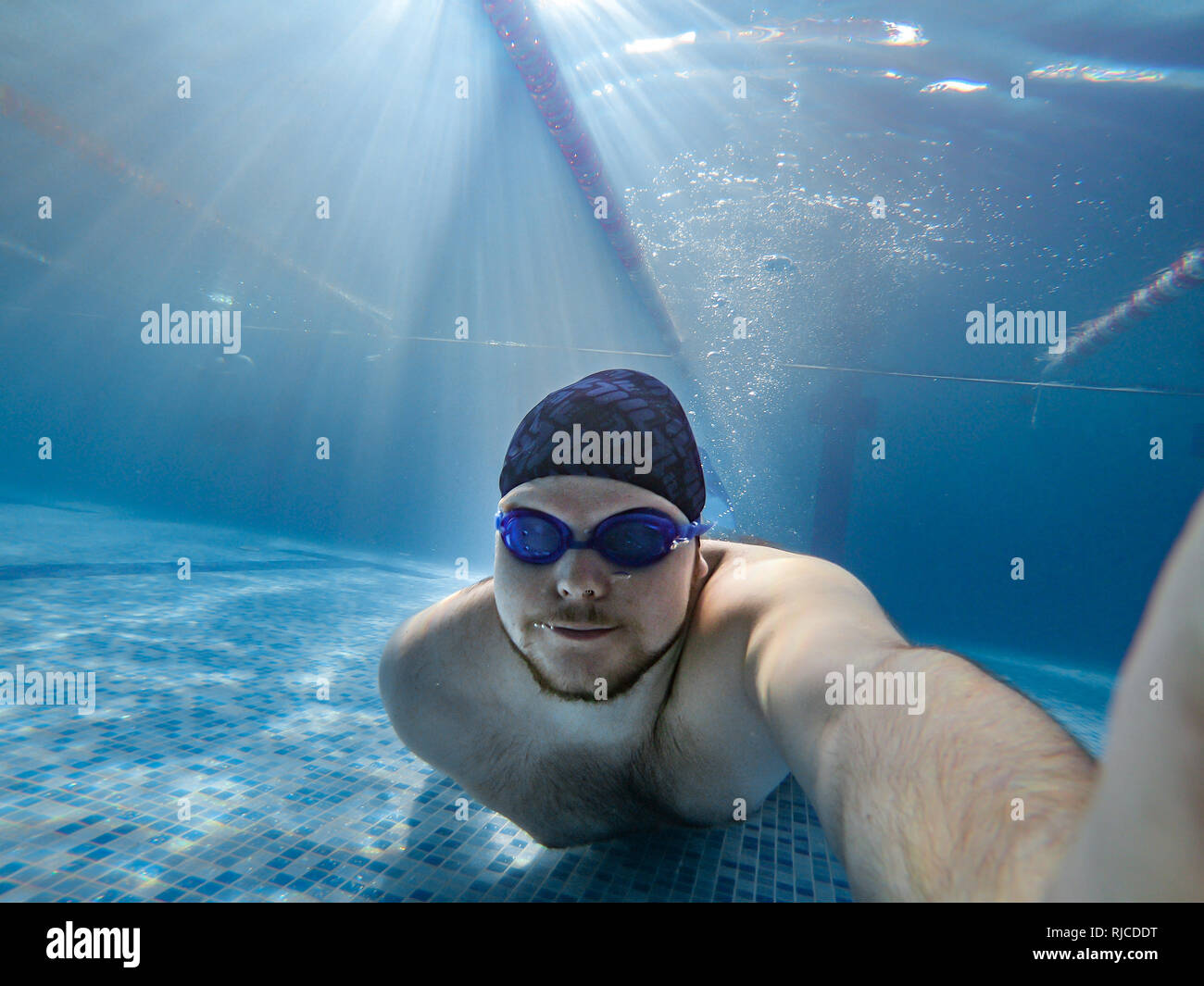 man underwater holding breath in pool. blue goggles Stock Photo - Alamy