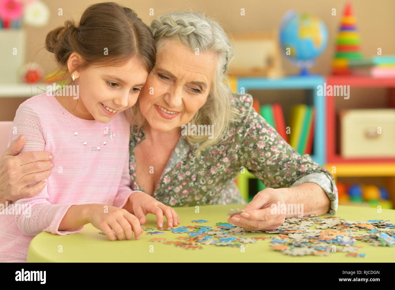 Portrait of grandmother collecting puzzle with her granddaughter Stock ...