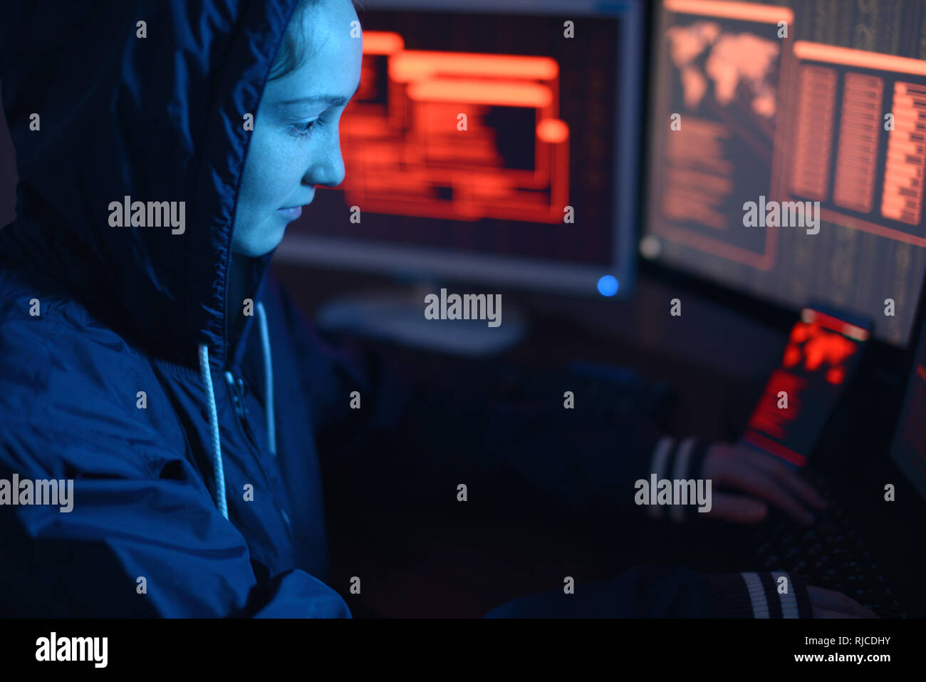 Girl Hacker In A Hood Typing Program Code While Committing A Cybercrime