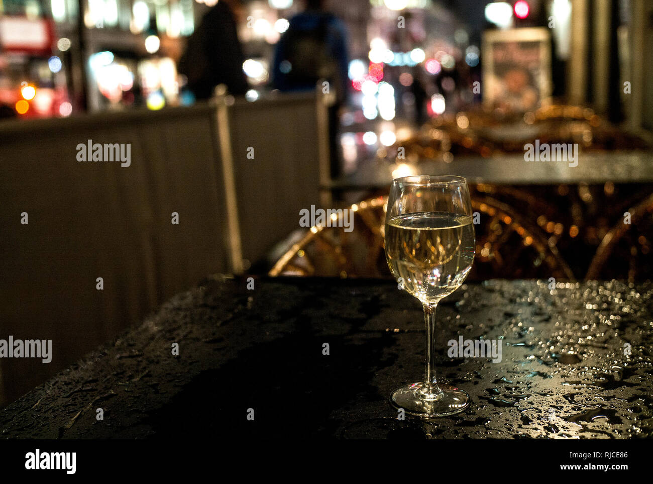 wine glass on rain drenched roadside table at night in the city Stock ...